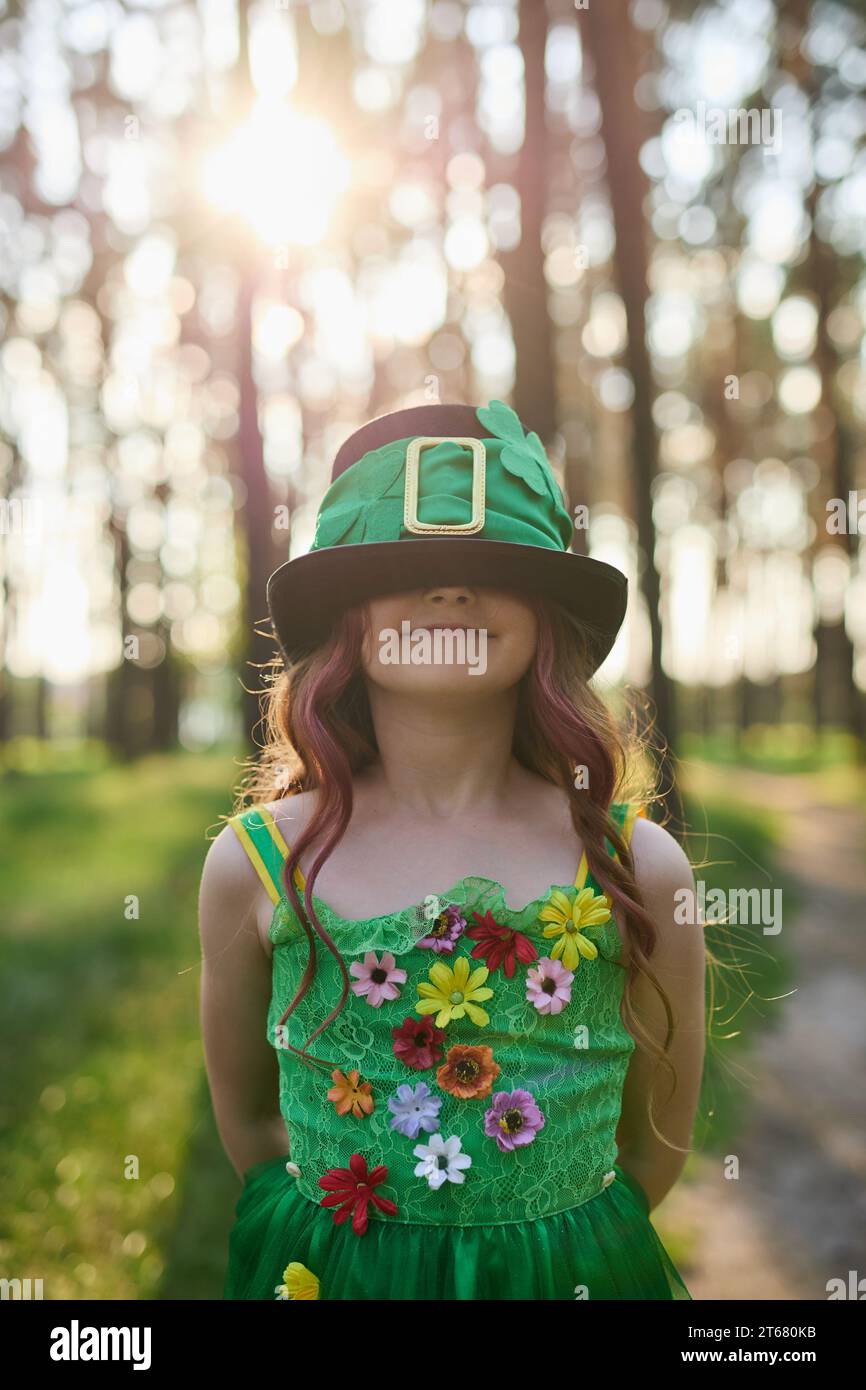 Adorable little girl in a leprechaun costume. Cute redhead child in cylinder har and green fairy ...