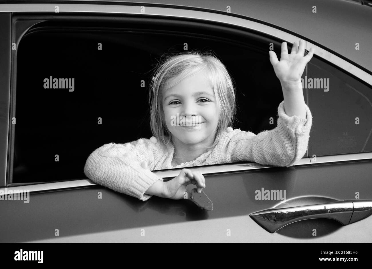 A little girl is sticking her head out the car window. Road trip or ...