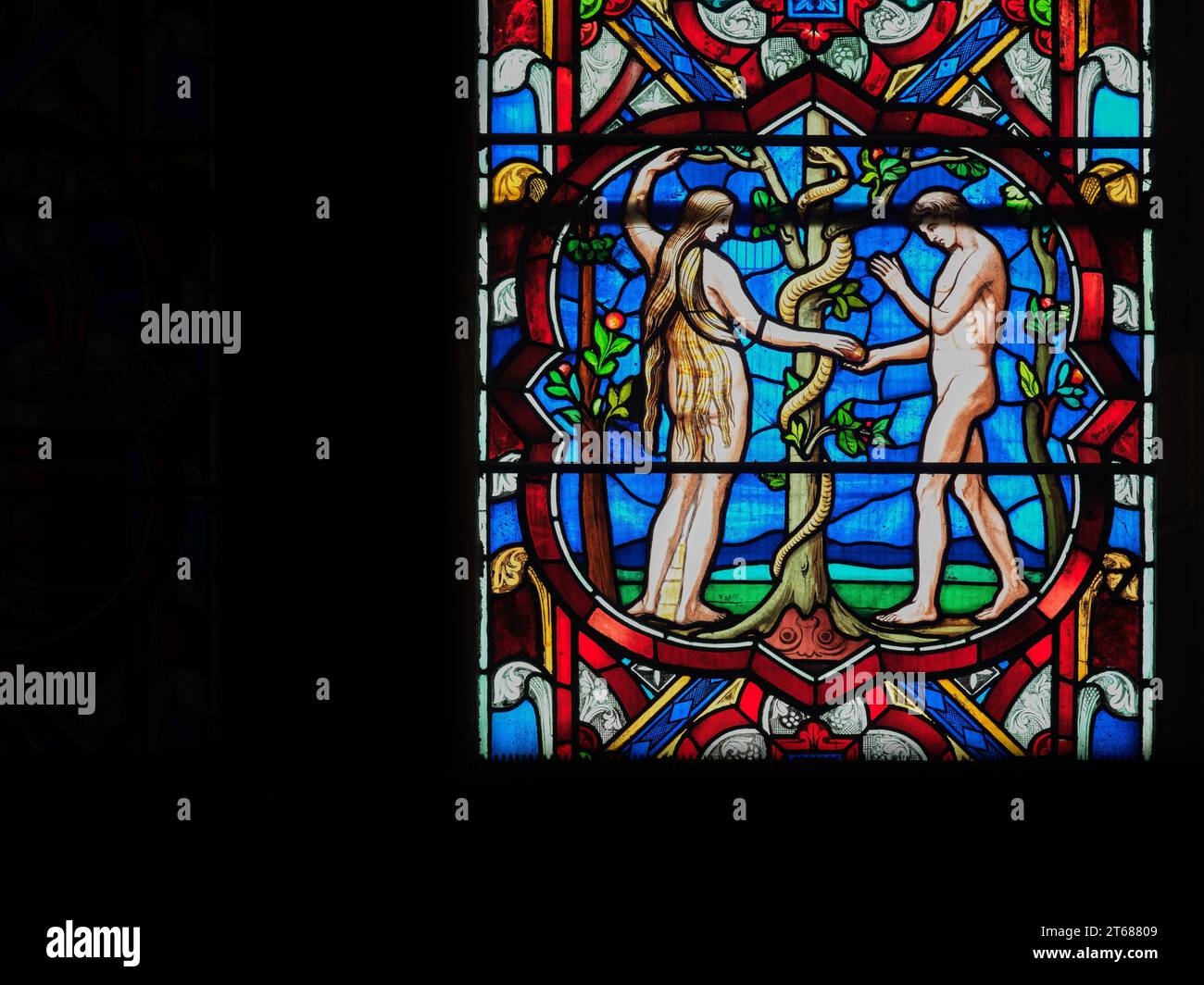 Eve gives Adam an apple, with the devil laughing; detail on the east stained glass window at ...