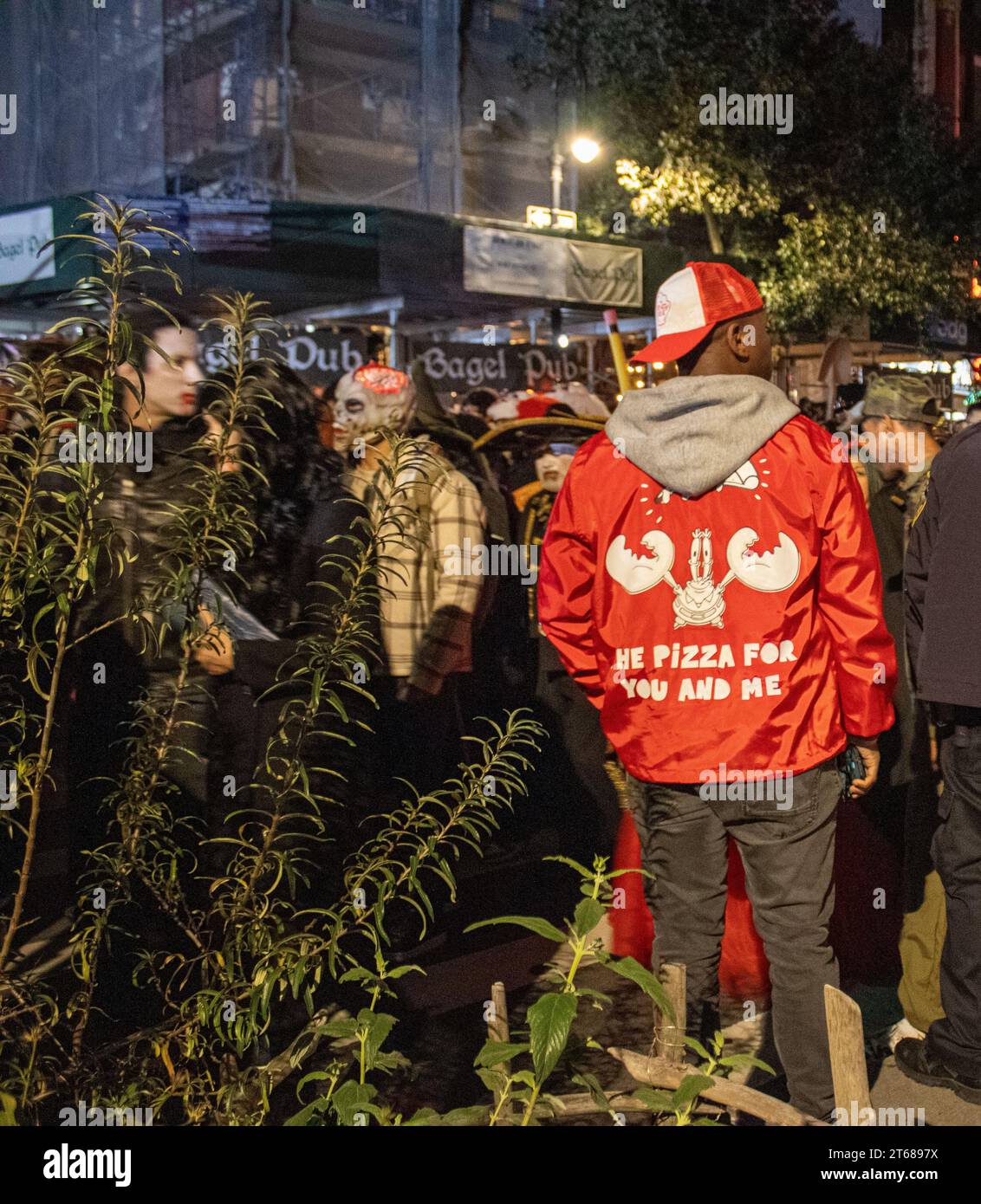 A diverse group of people gathered outside of a bar in the evening ...