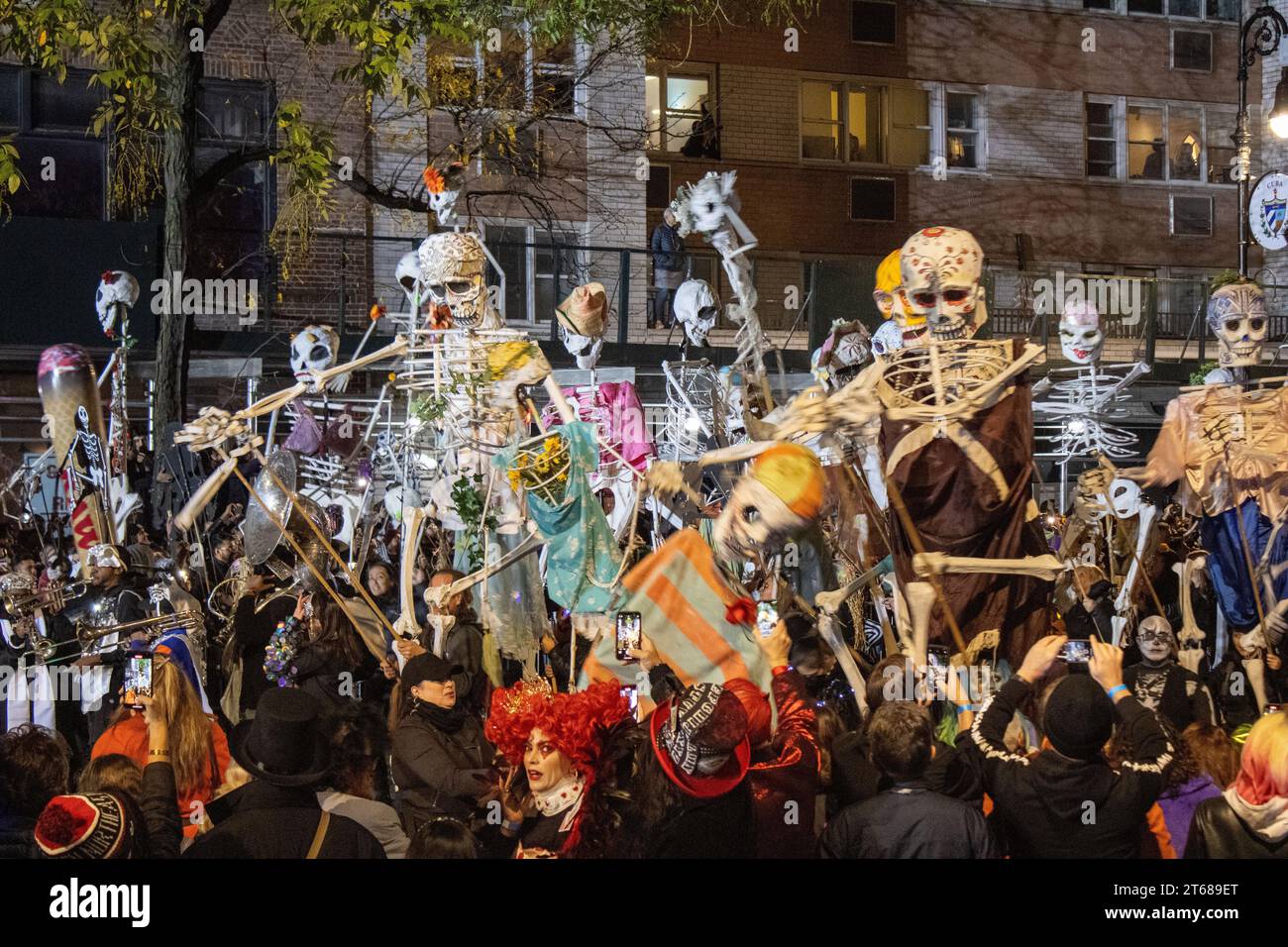 A group of people dressed in costumes stand on a street at night, with ...