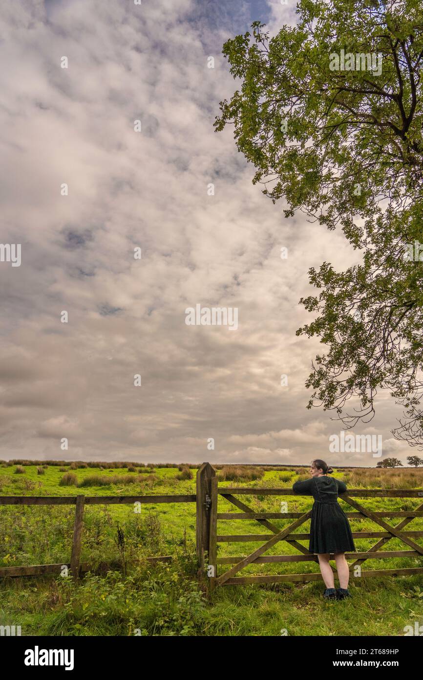 girl stood leaning against 5 bar gate contemplating life in the ...