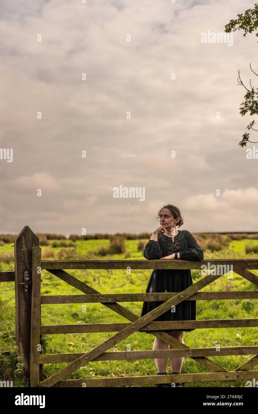 girl stood leaning against 5 bar gate contemplating life in the ...