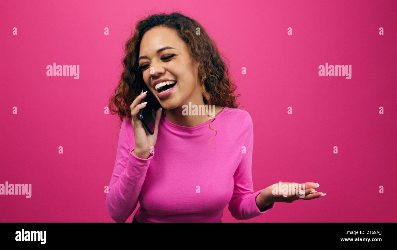Happy young woman answers phone, has positive conversation laughing and ...