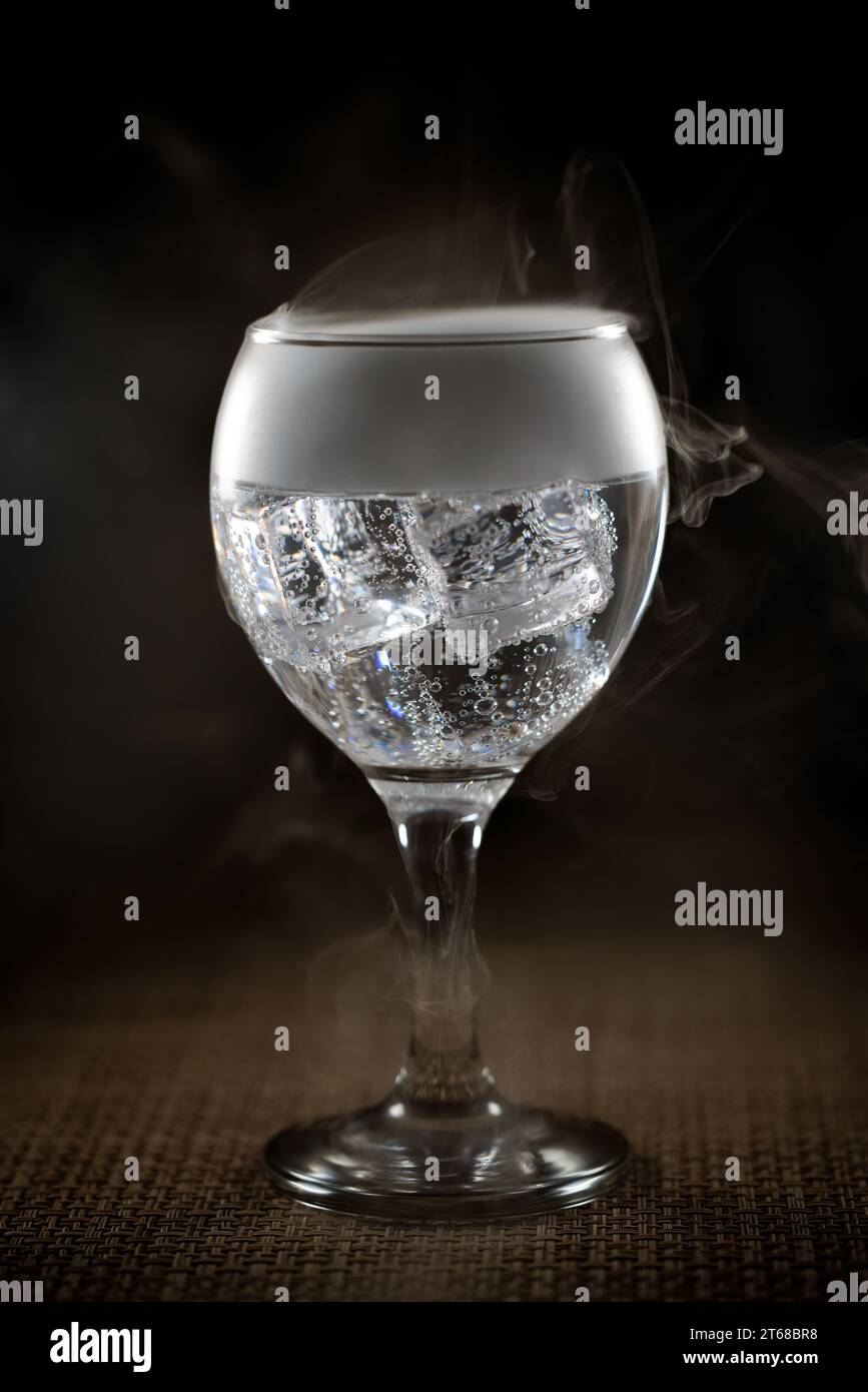 A glass of clear liquid with a shadowed background, conveying a sense ...