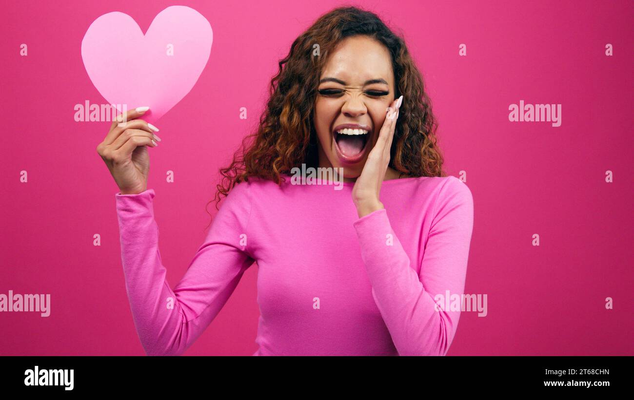 Surprised young woman finds love, shocked face looking at heart, studio ...