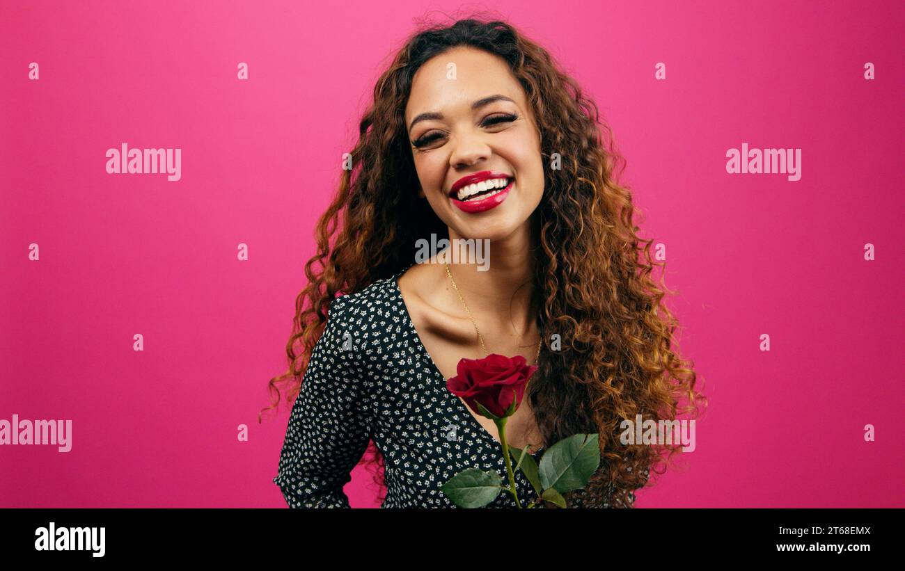 Beautiful multi-ethnic woman smells red rose, laughing and smiling ...