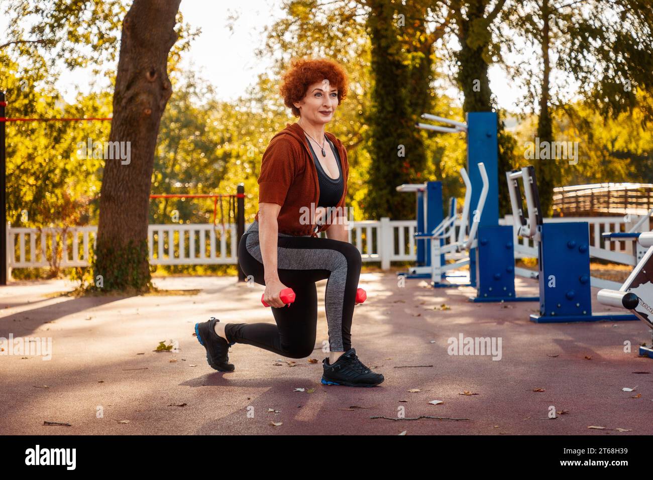 Adult Caucasian pretty woman is doing sports in park on street. Athlete ...