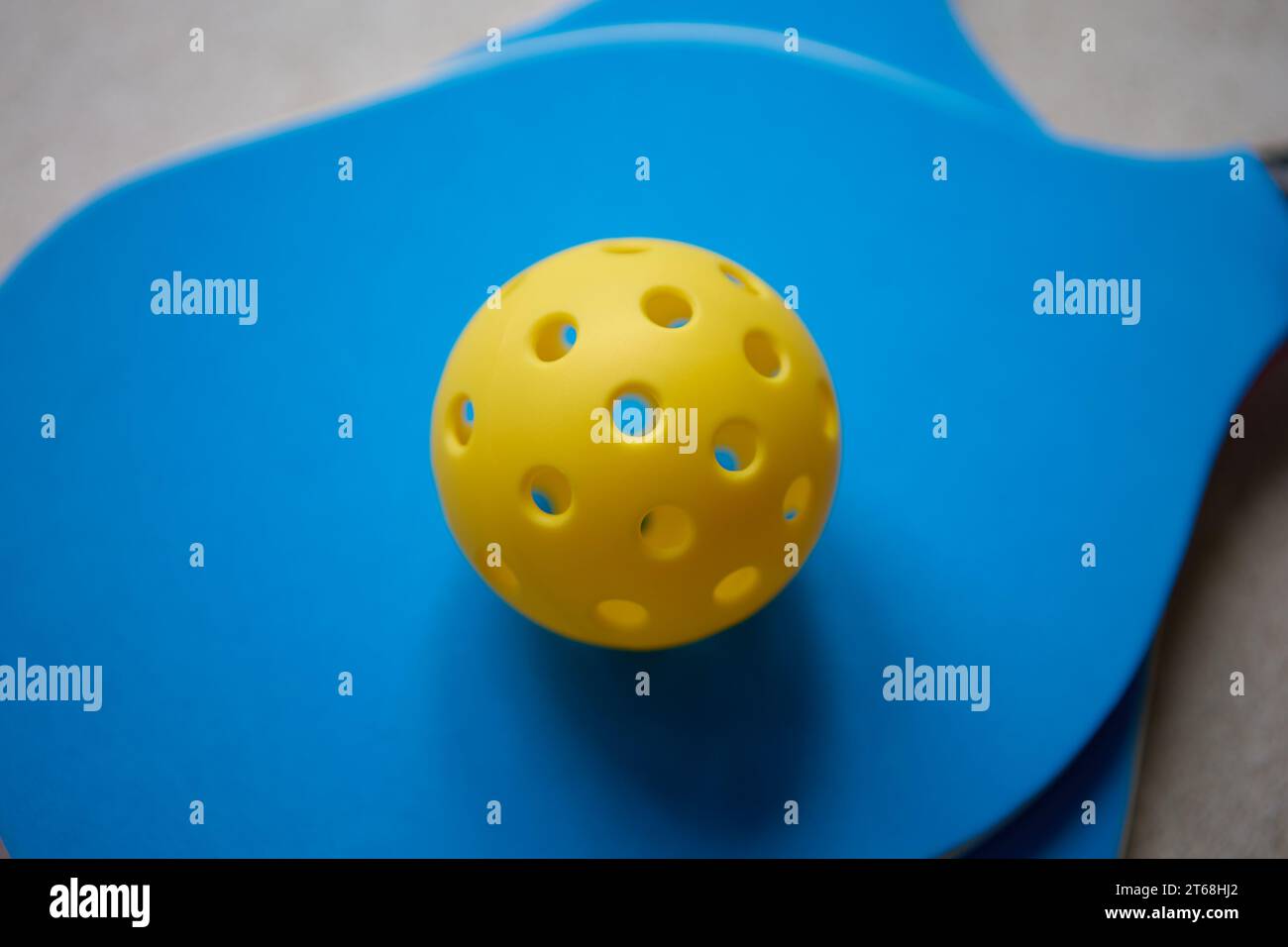 Perforated plastic ball for pickleball photographed on rackets Stock ...
