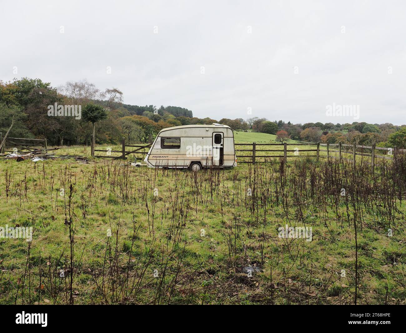 An old touring caravan parked in a farmer's field with damaged and ...