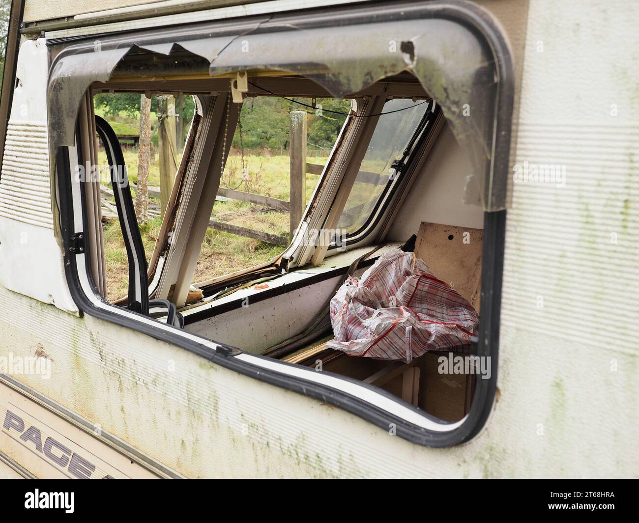 An old touring caravan parked in a farmer's field with damaged and ...