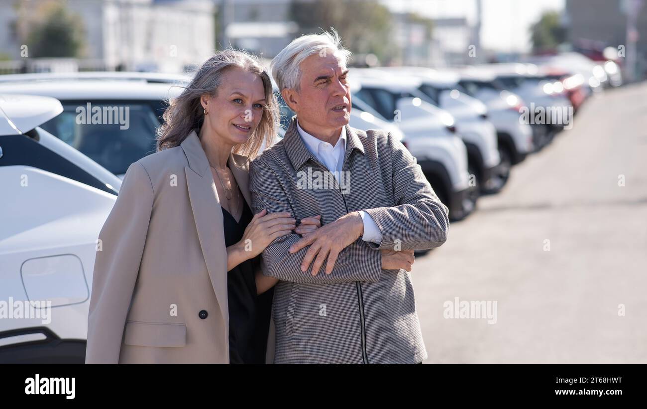 Mature Caucasian Couple Walks Past Cars Outdoors Choosing A New One