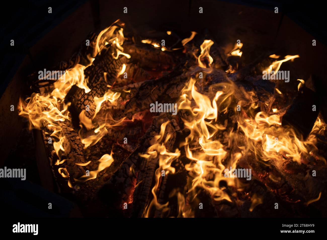 Big bonfire at night. Firewood burns in open air. Yellow flame. High ...
