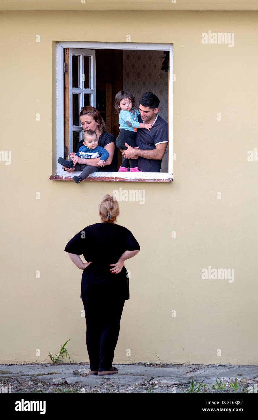 Sighnaghi, Georgia - October 7, 2023: A couple with small childrens talk through a window with a ...
