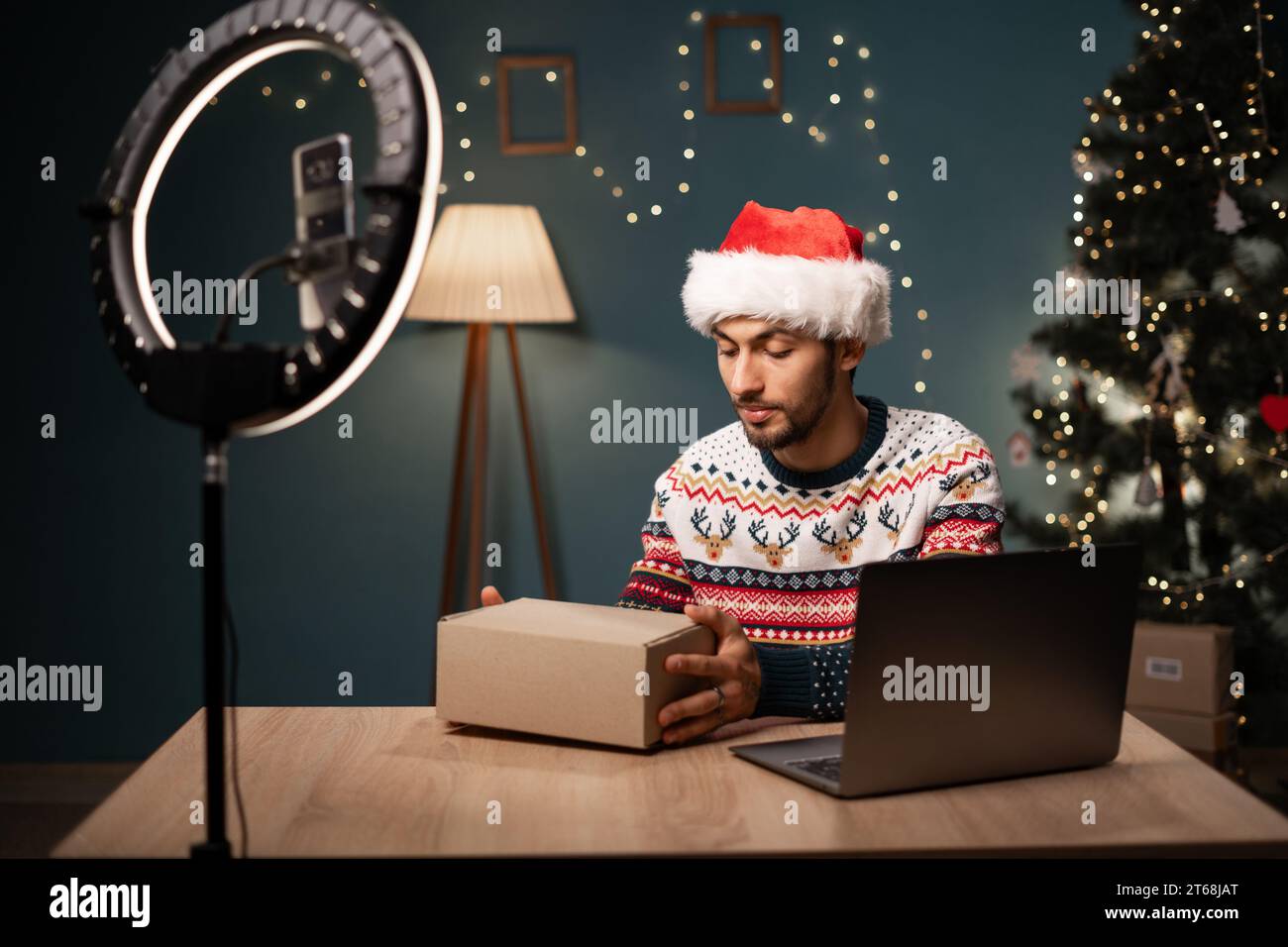 Happy arabic man social media channel blogger wear Santa hat recording unboxing parcel box, vlog ...