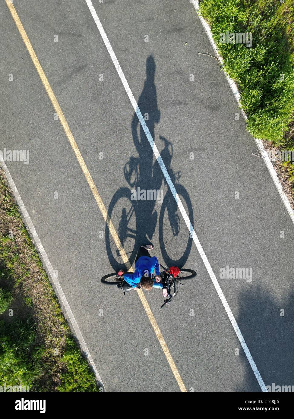 Two young male adults cycling side by side on a paved road, enjoying ...