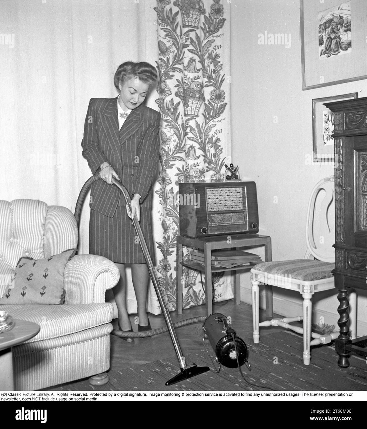 Vacuuming in the 1940s. A women dressed in a typical 1940s outfit is ...