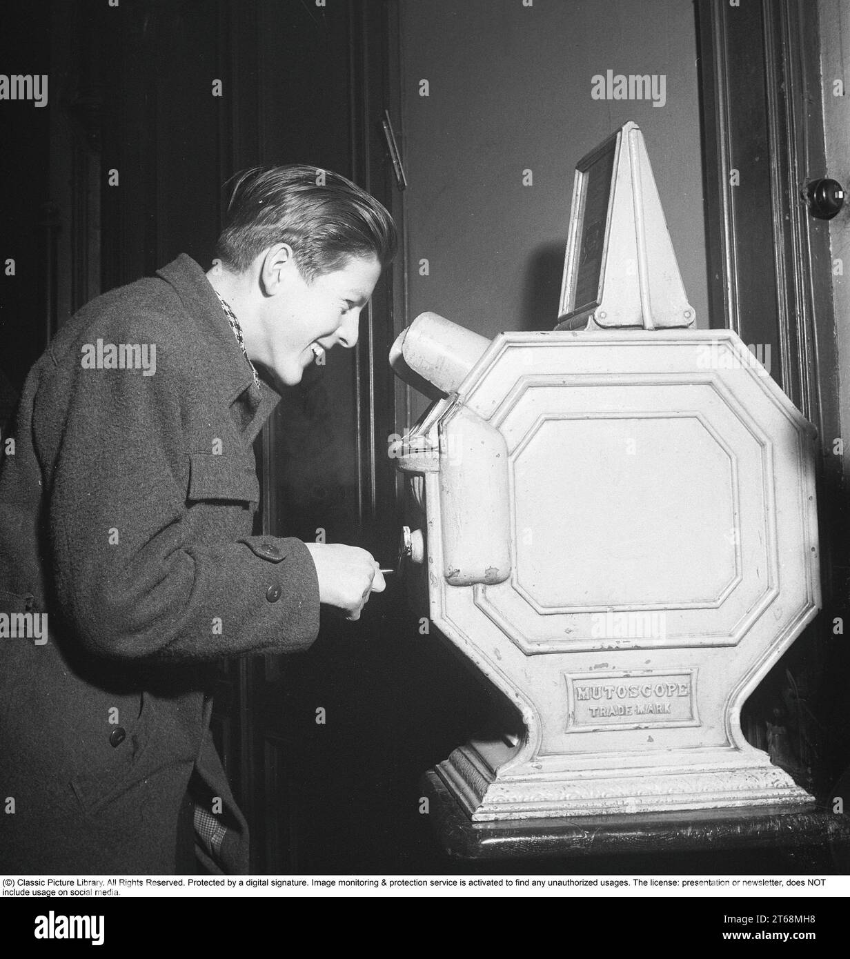 Young man at a Mutoscope, an early motion picture divice invented in ...