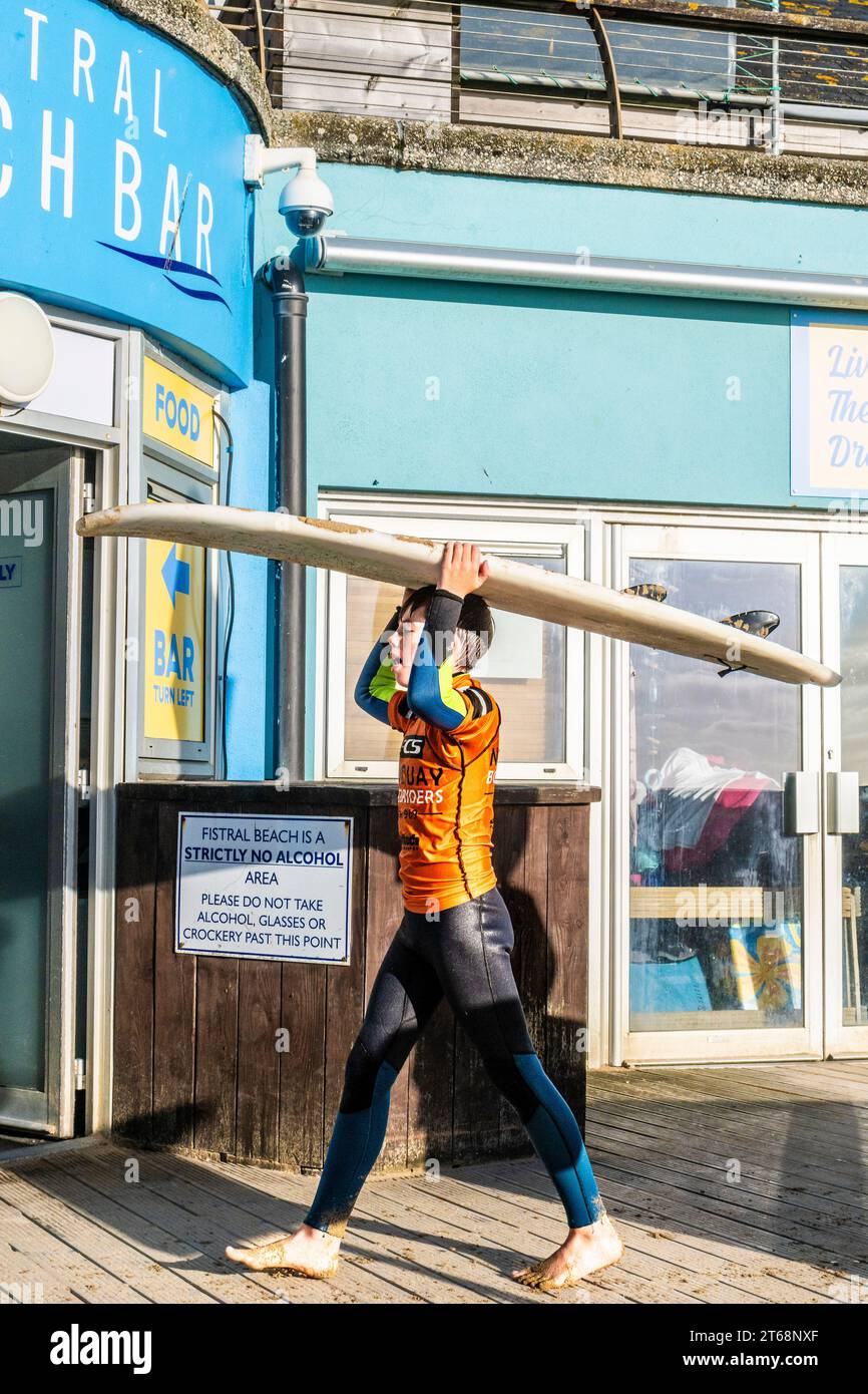 A young male surfer balancing a surfboard on this head walking home ...