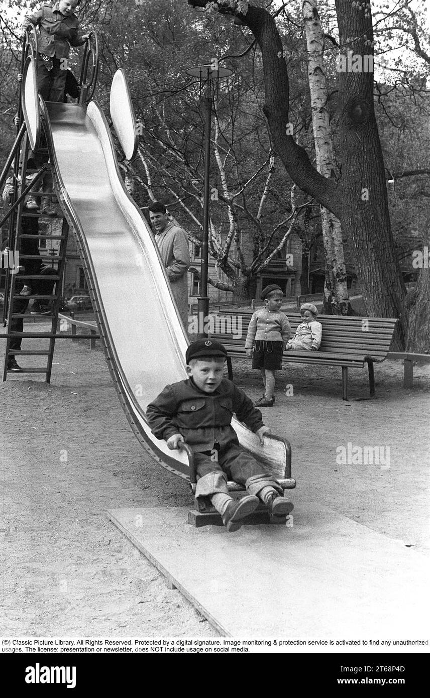 Playground in the 1950s. Children are seen coming down a slide in a ...