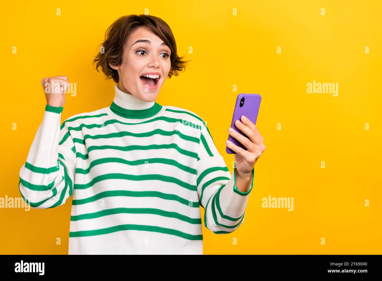 Photo of delighted funky girl hold use smart phone raise fist success ...