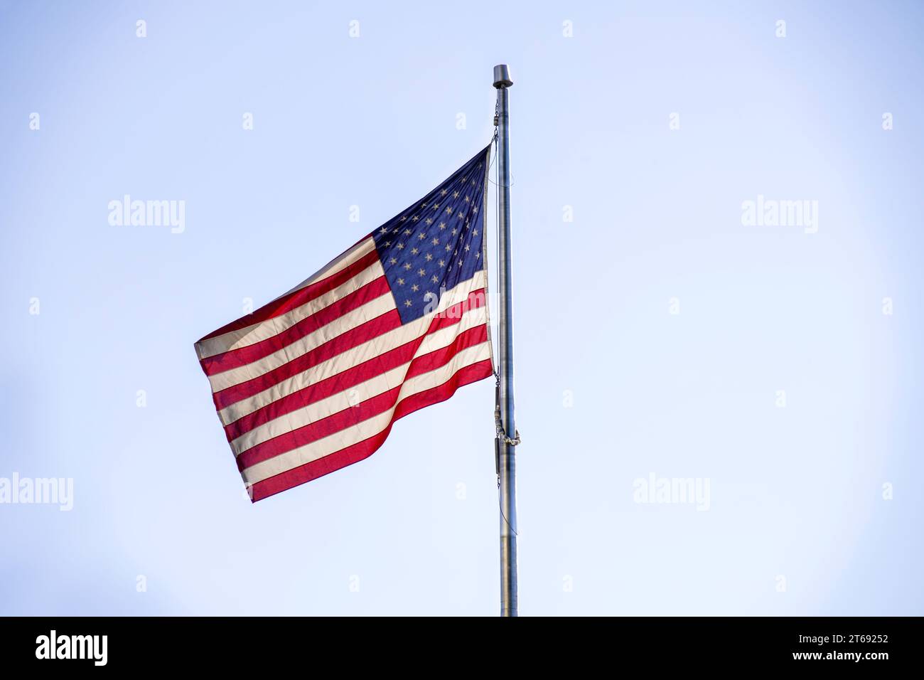 American flag waving in wind on flag pole. The national red, white and ...