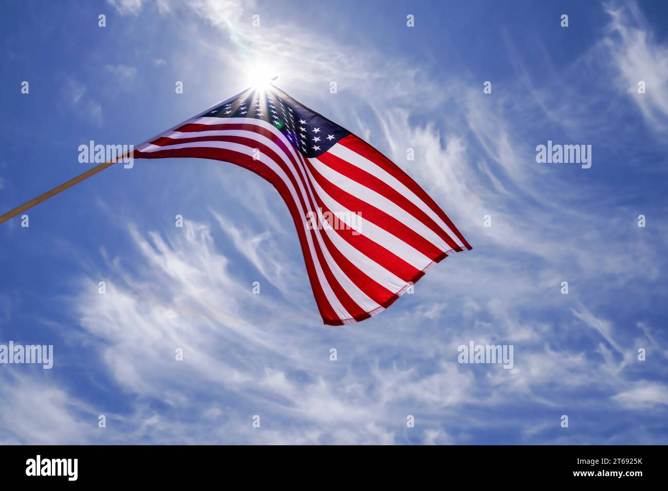 American flag waving in a streaked clouds blue sky with a starburst ...