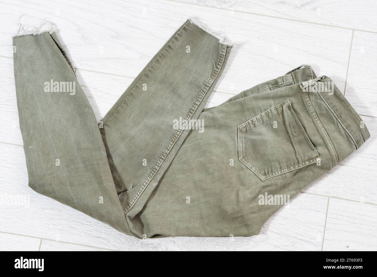 green folded pants on wooden table top view, khaki jeans, khaki denim ...