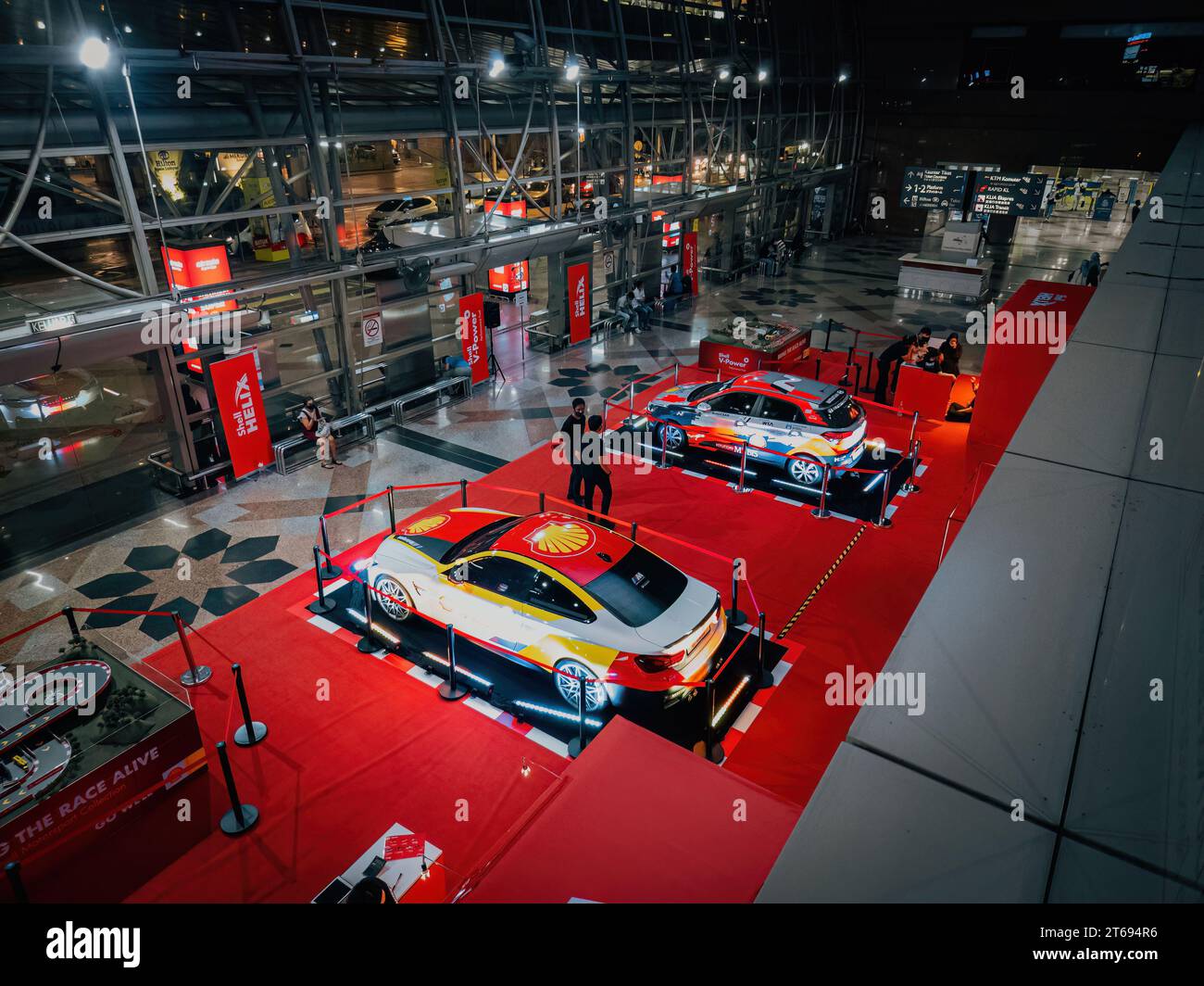 A group of cars parked on a red carpet-covered race track illuminated ...