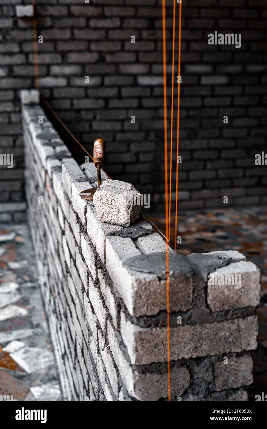 A close-up of a red brick wall with exposed pipes and wires in a ...