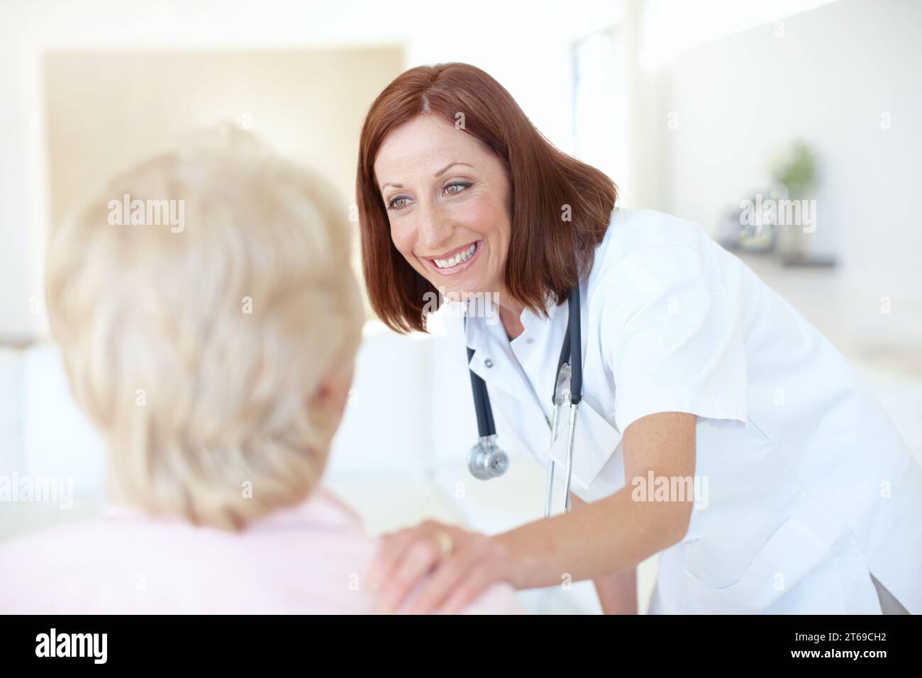 A quick checkup on a patients progress. Friendly mature nurse comforts ...