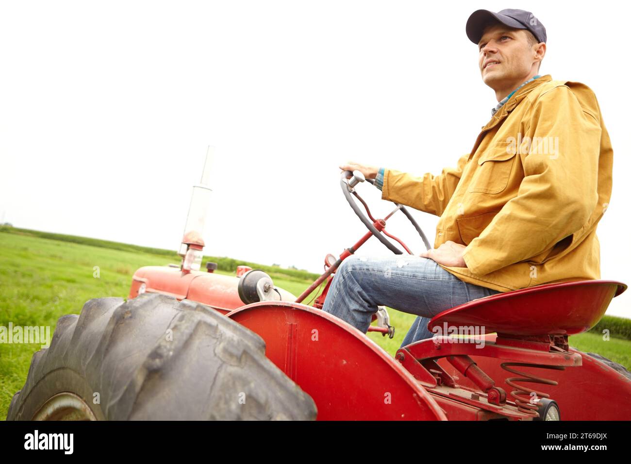 Sitting in contemplation. A farmer sitting on his tractor and looking ...