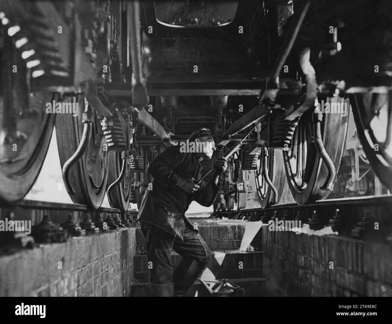 A worker uses a syringe to press oil onto the moving parts of a steam ...