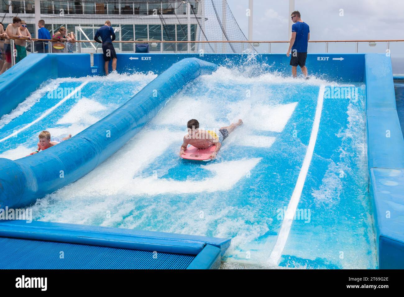 Young male cruise passengers on surfboards in the Flowrider activity on ...