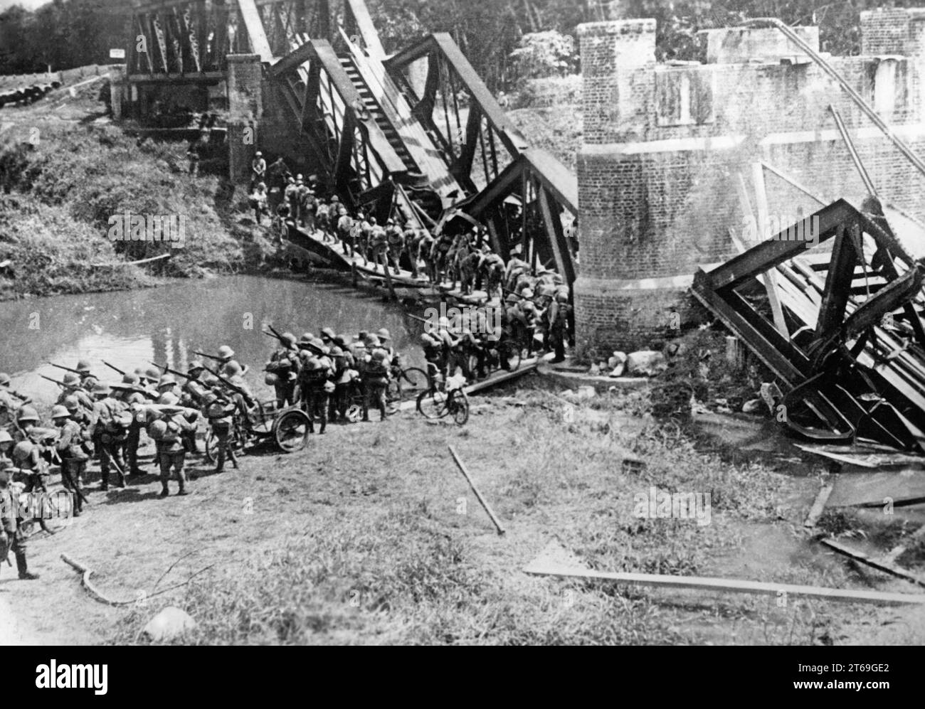 Japanese soldiers cross a river in Burma on a footbridge after the ...