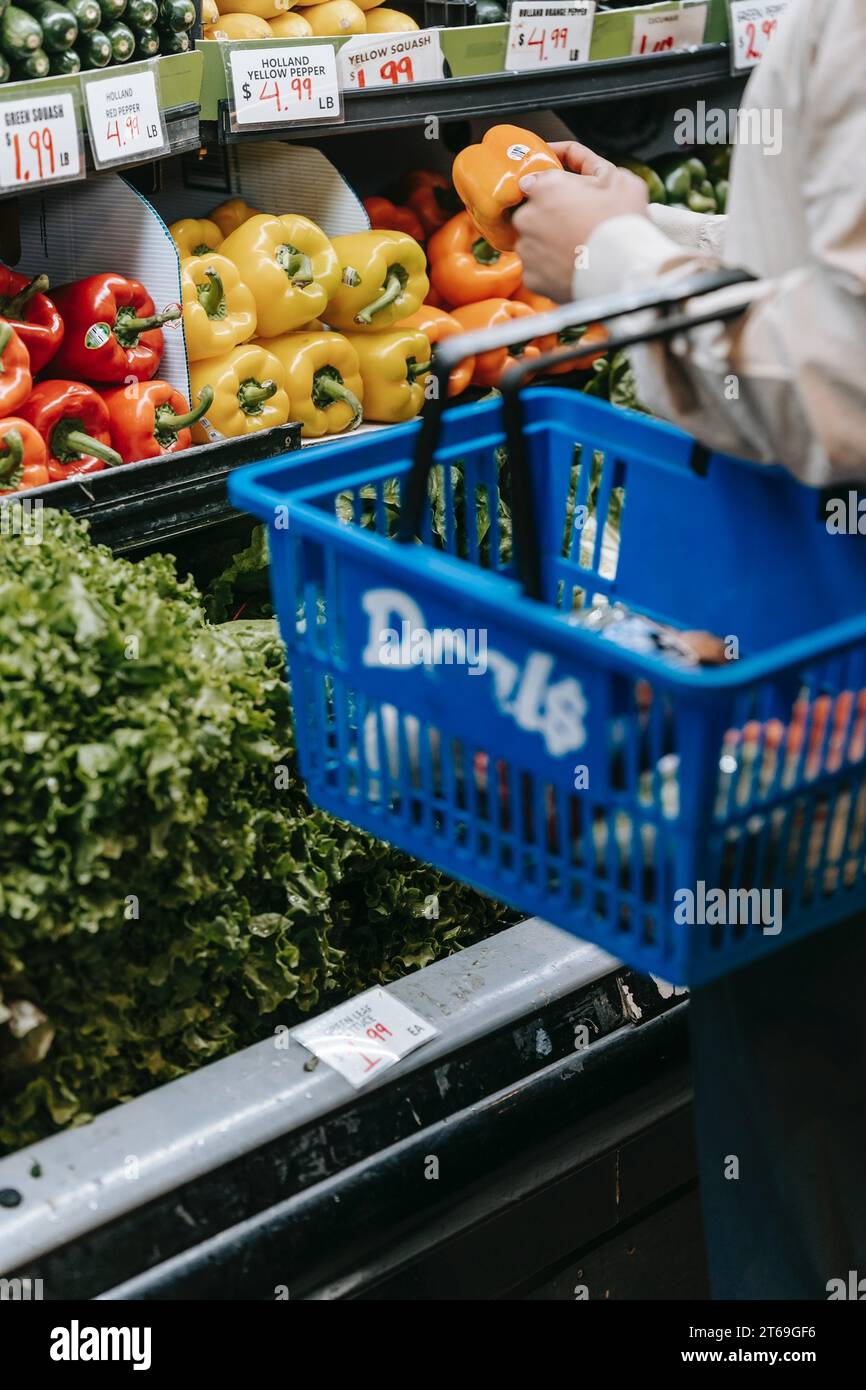 An adult shopper selecting a variety of fresh vegetables from a grocery ...