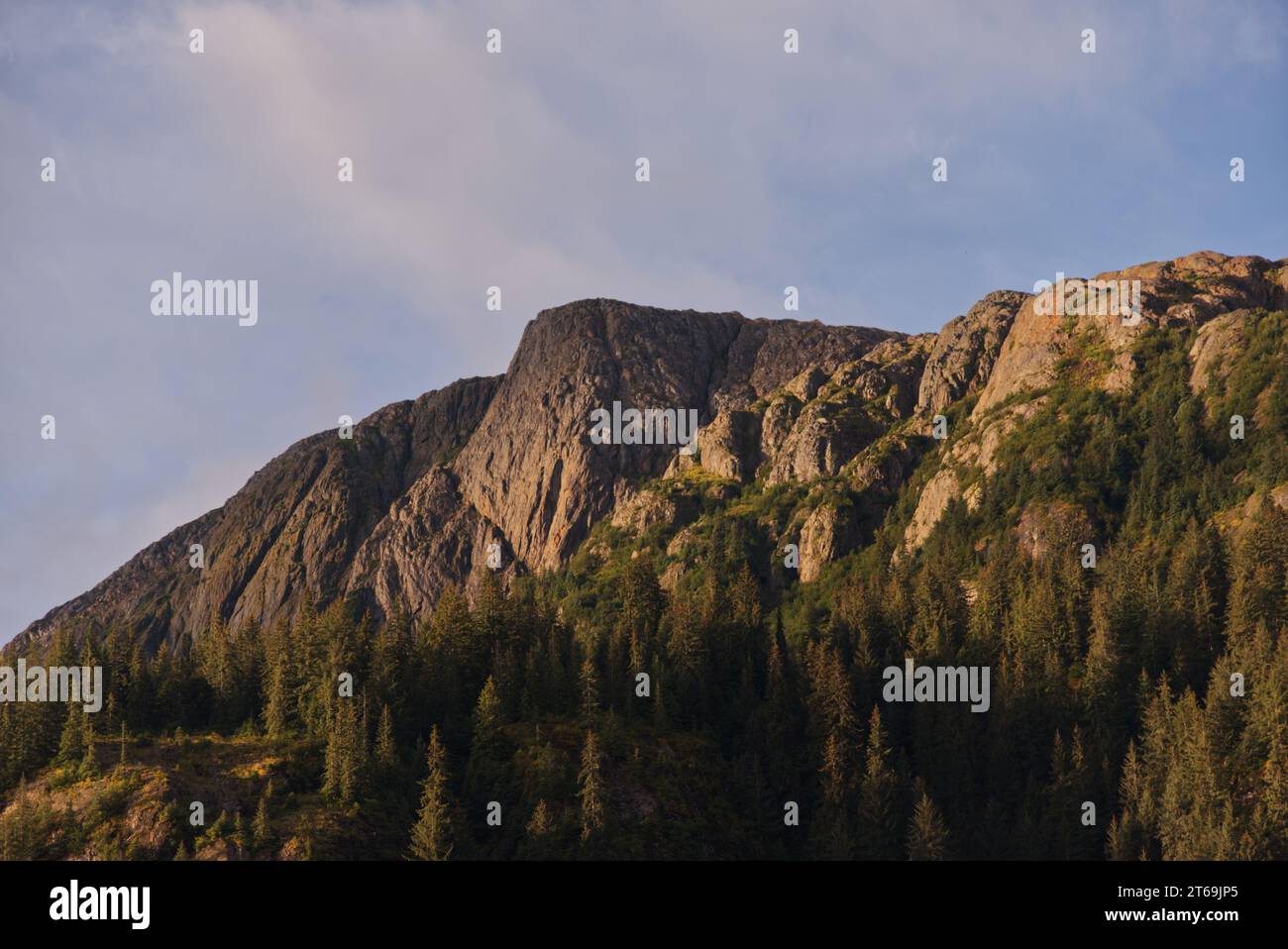 A scenic view of an outdoor landscape with tall mountains, lush trees ...