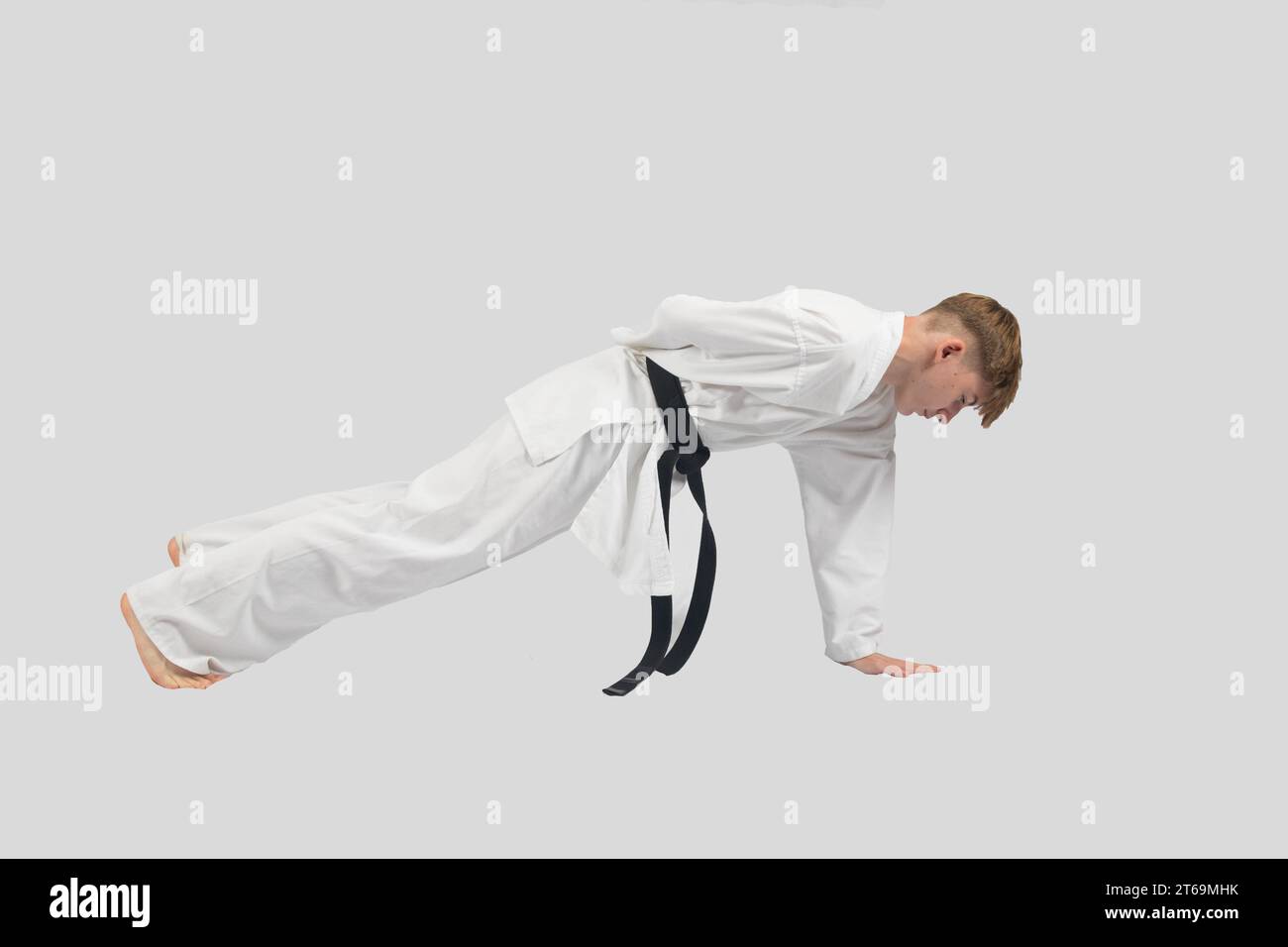 Black belt teenage boy doing a one handed push up Stock Photo - Alamy