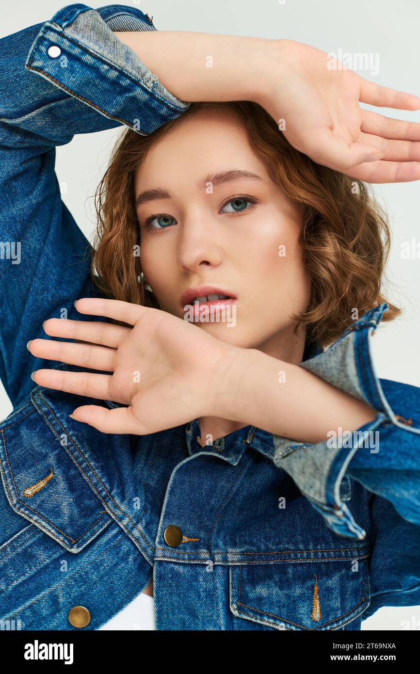 portrait of attractive young model in cropped denim jacket gesturing ...