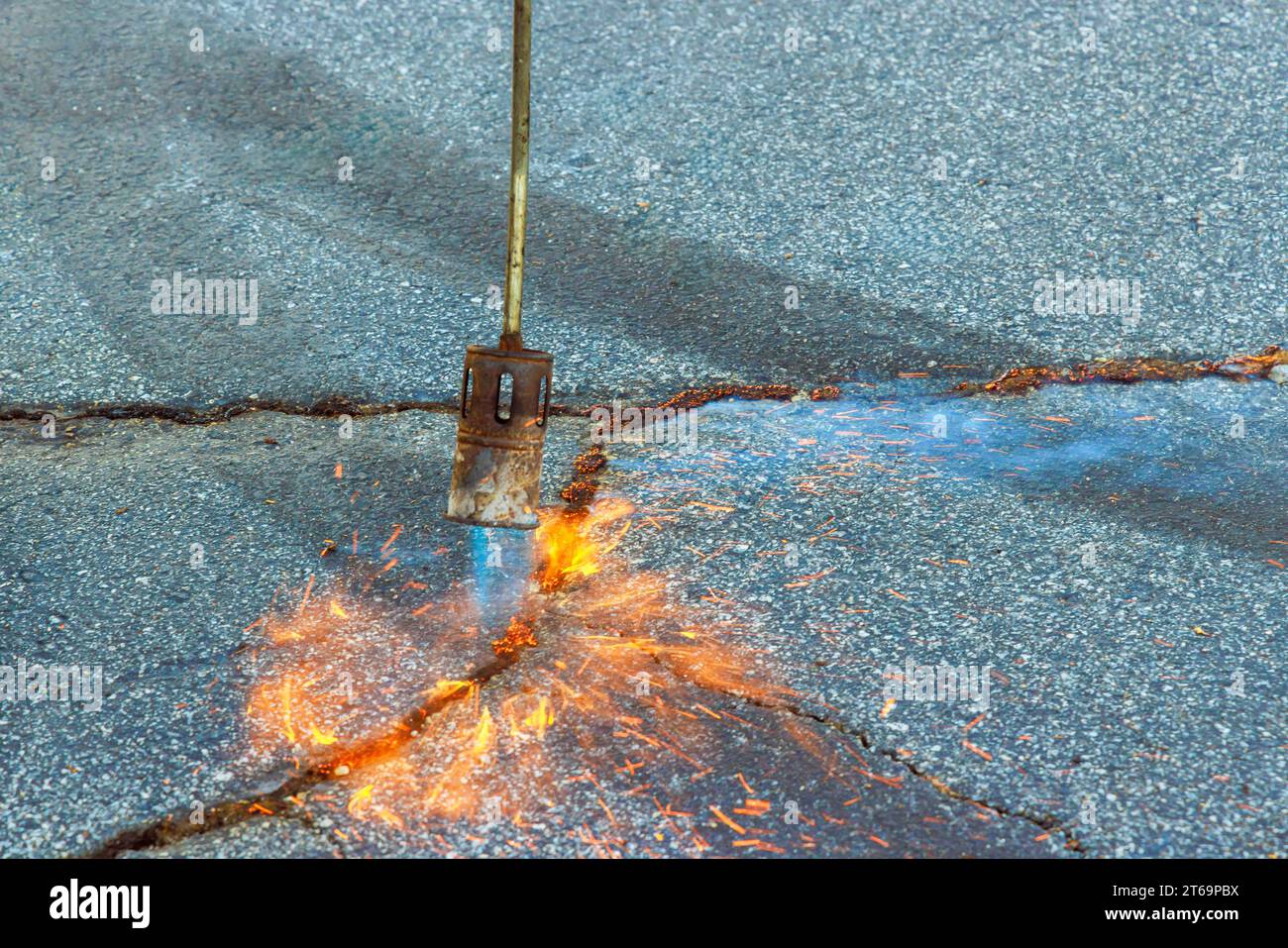 Asphalt patcher performs restoration work in cracks of road surface by ...