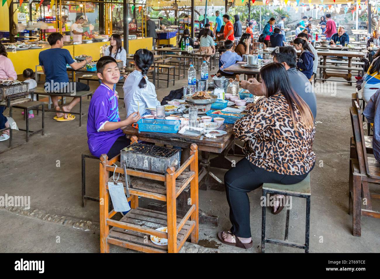 Thai family cooking food on charcoal grill and hot pot at their table ...