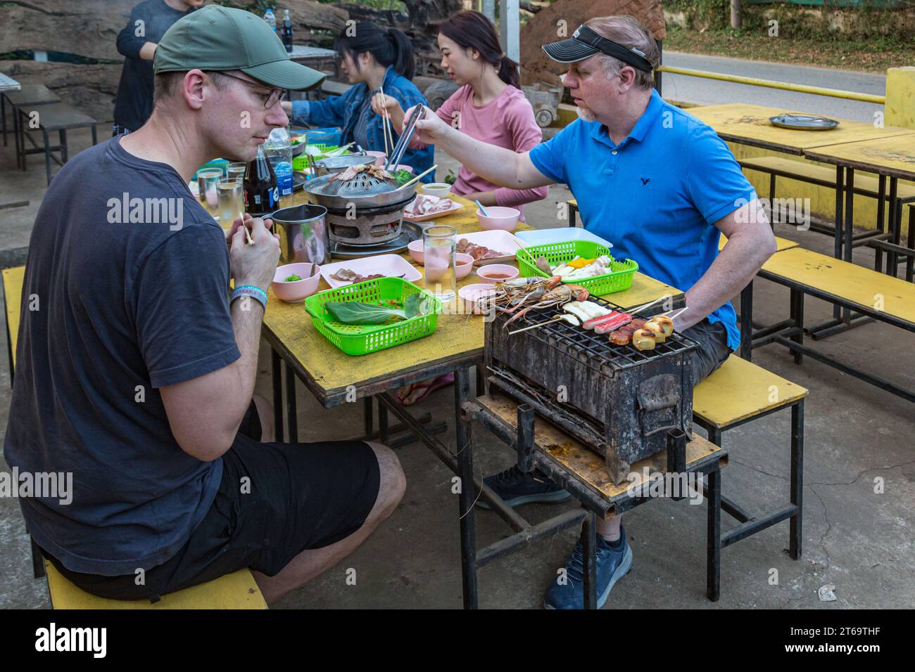 American missionaries cooking food on a charcoal grill and hot pot at a ...