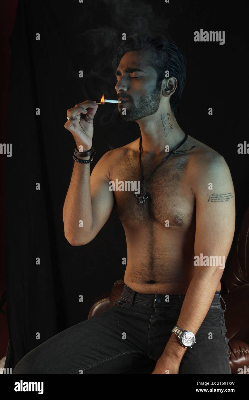 Handsome young man smoking cigar and looking away Stock Photo - Alamy