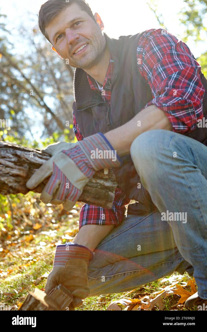 One mature lumberjack holding piece of wooden log after chopping tree ...
