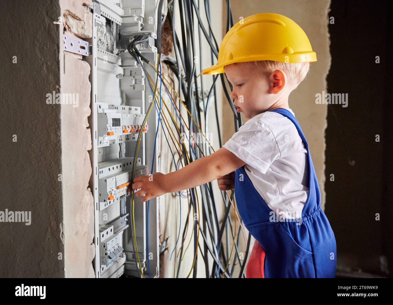 Side view of child fixing electrical switchboard or distribution board ...