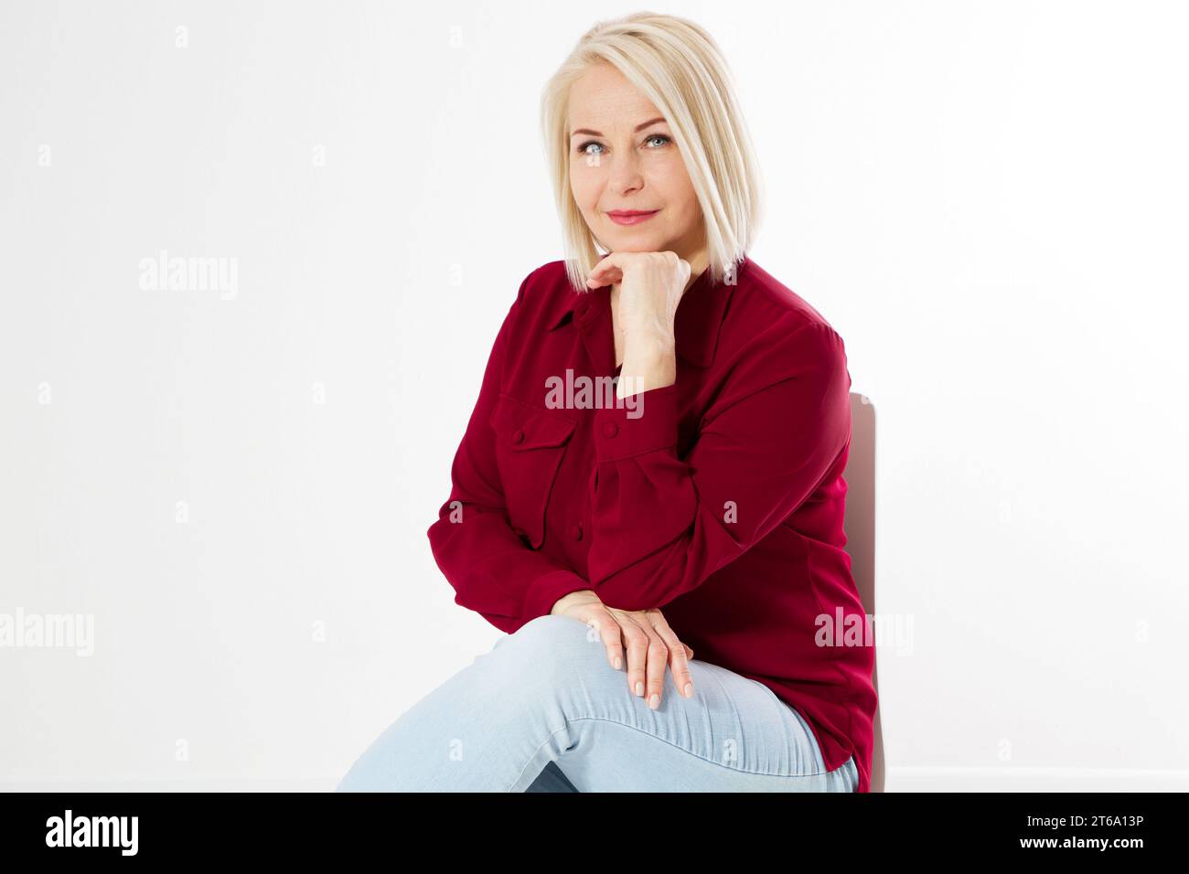 Close up portrait of smiling blond woman in stylish red shirt sitting ...