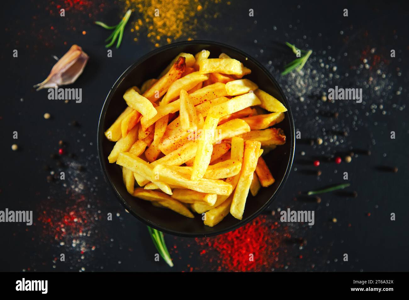 French fries with spices on a black background. Food background, flat ...