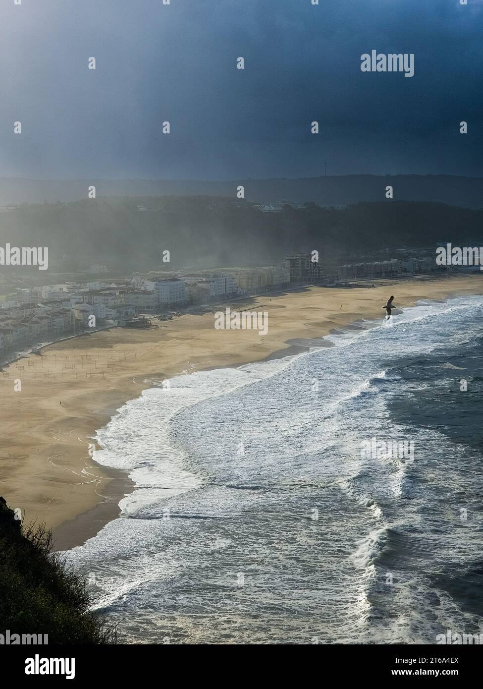 Two people enjoying a fun day of surfing in the rain and fog on a beach ...