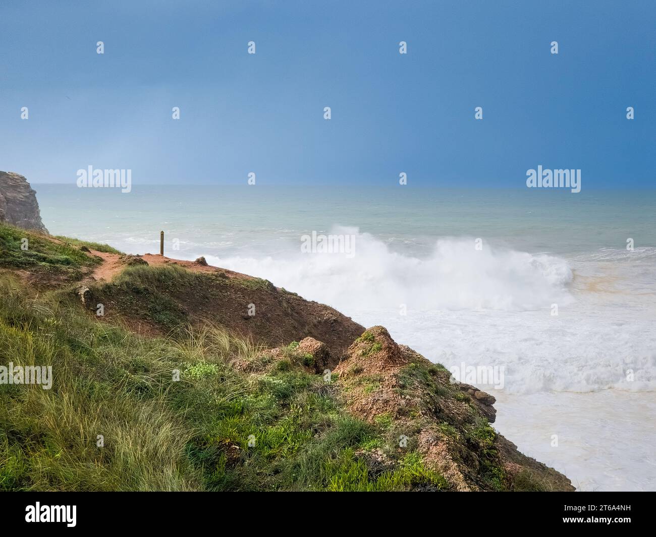 A man stands atop a cliff, gazing out at the vast ocean below Stock ...
