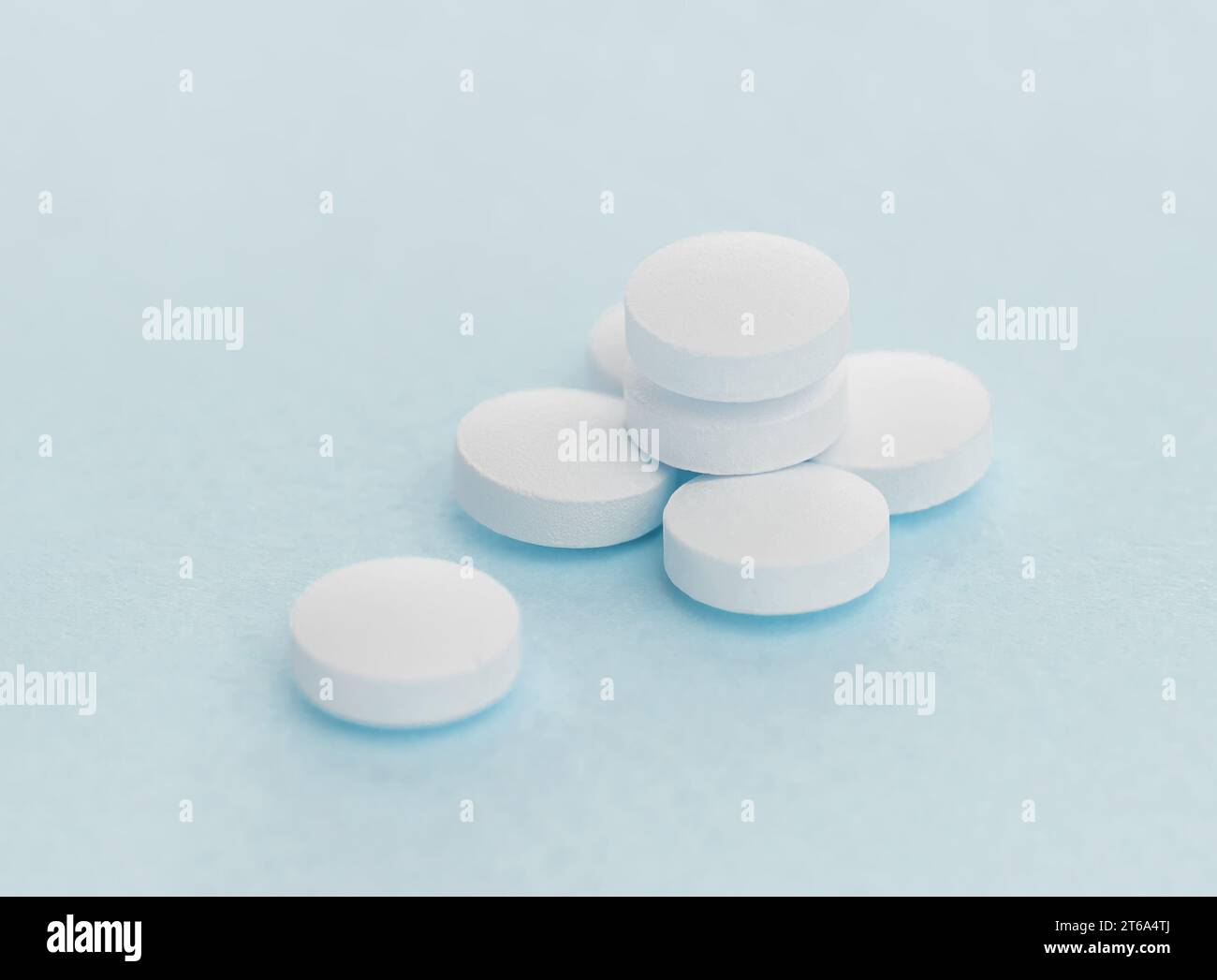 White pills spilled on blue pastel coloured background. Medication and ...